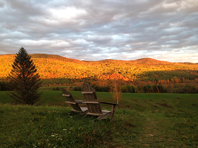 Adirondack chairs perfectly positioned to capture the golden hour light across Vermont's rolling mountains – nature's version of front-row seats.