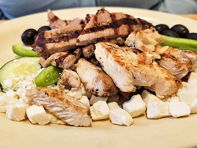 A Greek salad that means business, with grilled chicken, feta crumbles, and olives playing harmoniously on a sunny plate.