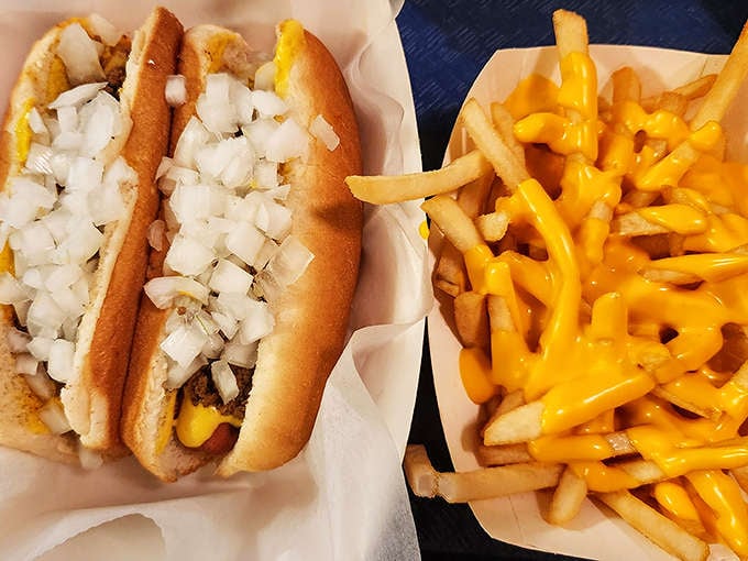A match made in comfort food heaven: two Coney dogs nestled beside golden fries smothered in molten cheese that stretches with each delicious forkful.
