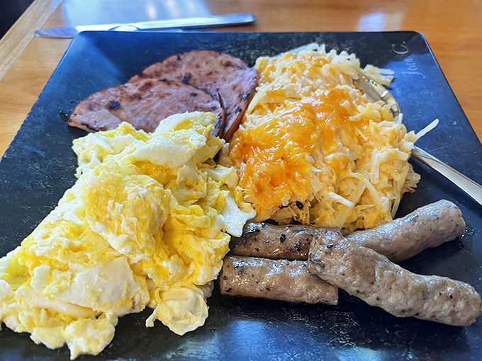 Fluffy scrambled eggs and savory breakfast meats share the plate with hash browns that achieve the impossible: crispy outside, tender inside.