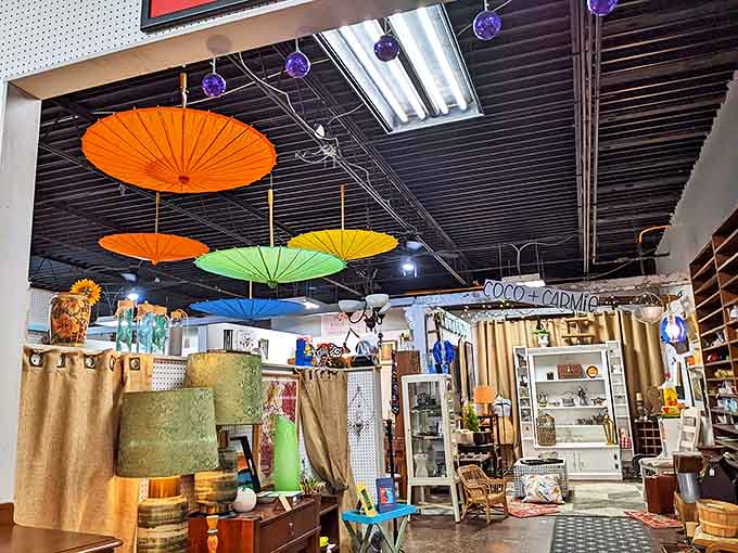 Colorful parasols dance overhead in this booth, creating a whimsical canopy above vintage furniture and collectibles.