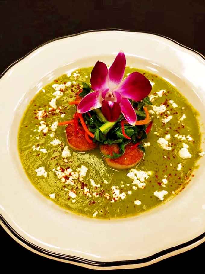 This vibrant green soup, adorned with an orchid and scallops, proves The Alcove's culinary prowess extends well beyond beef.