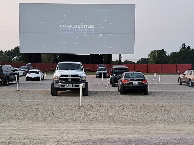 The massive screen at Capri Drive-In stands ready for showtime as cars line up in rows for a day of outdoor movie magic.