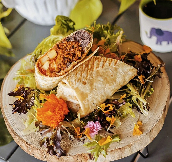A beautiful presentation elevates the humble burrito to centerpiece status, surrounded by fresh greens and edible flowers.
