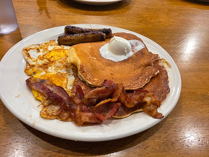 The breakfast platter that launched a thousand road trips: pancakes, eggs, bacon, and sausage in perfect harmony.