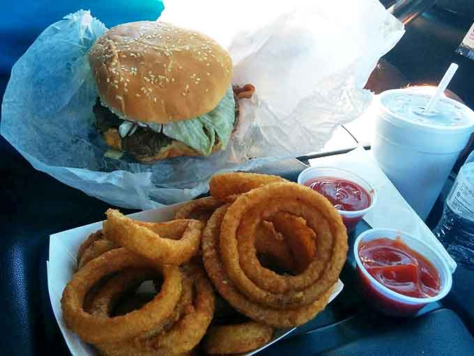 Those onion rings aren't just sides, they're golden halos of crispy perfection that complement the star attraction with their sweet-savory crunch.