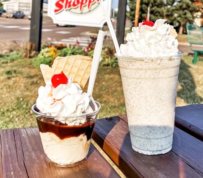 Caramel Sundae and Oreo Malt: Sweet companions on a wooden table—one a layered caramel dream, the other a cookies-and-cream masterpiece topped with cloud-like whipped cream.