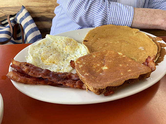 The classic breakfast trifecta: eggs with just-right yolks, bacon cooked to perfection, and pancakes that deserve their own fan club.