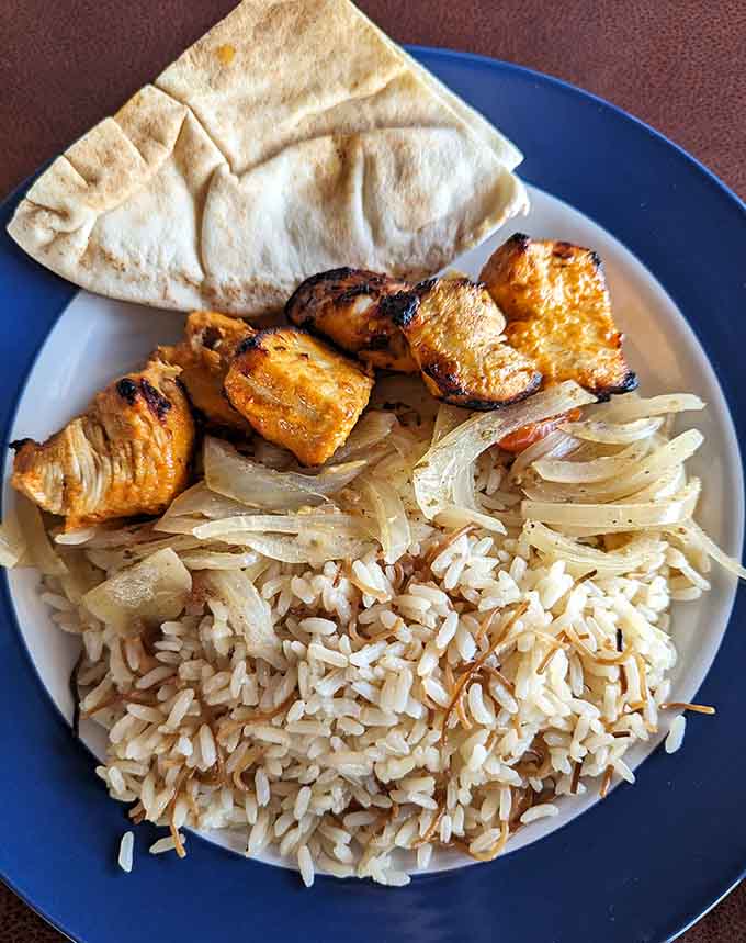 This generous portion of kabobs with rice and pita shows why people keep coming back for more of the same thing.