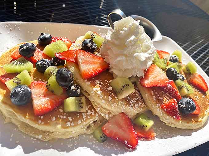 Pancakes that deserve their own fan club, topped with a rainbow of fresh fruits and a cloud of whipped cream.
