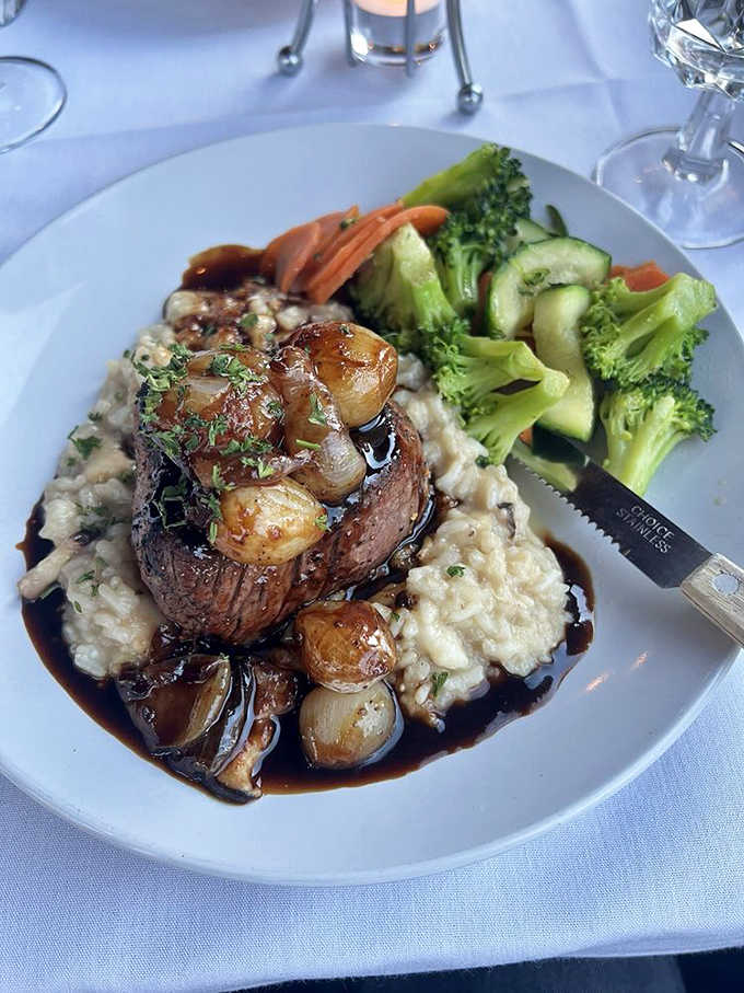 A filet mignon nestled on creamy risotto with pearl onions creates a tableau of comfort and luxury &ndash; proof that some food combinations are simply meant to be together.
