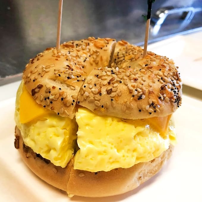 The breakfast sandwich stacked high with fluffy eggs and melted cheese turns an everything bagel into a handheld masterpiece of morning fuel.