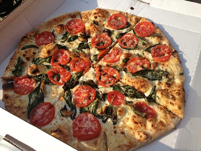 Fresh tomatoes and basil dance atop a perfectly blistered crust – proof that sometimes the simplest combinations create the most profound flavors.