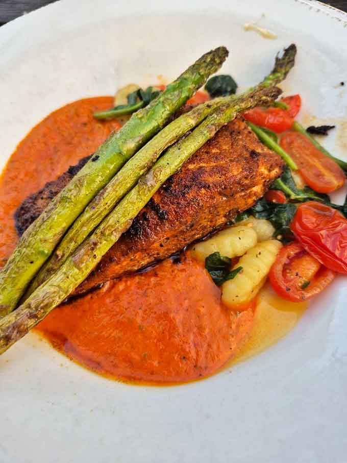 Perfectly seared salmon rests on a vibrant bed of vegetables, looking like it just stepped off the runway at Fashion Week for fish.