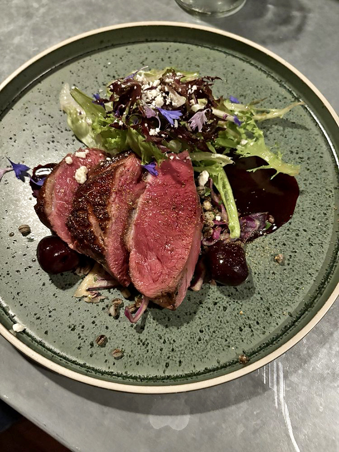 Slices of perfectly pink duck breast with a glistening glaze, accompanied by fresh greens &ndash; a masterclass in balancing richness with brightness.