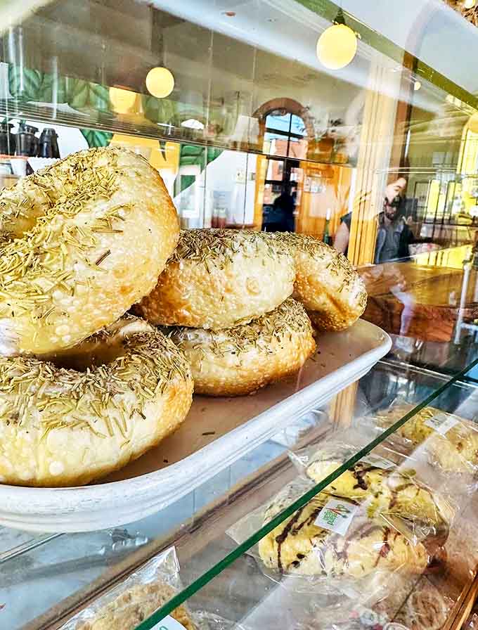 These aren't your average bagels &ndash; golden, herb-crusted beauties stacked like edible jewelry behind glass. Carb heaven awaits the hungry coffee seeker.