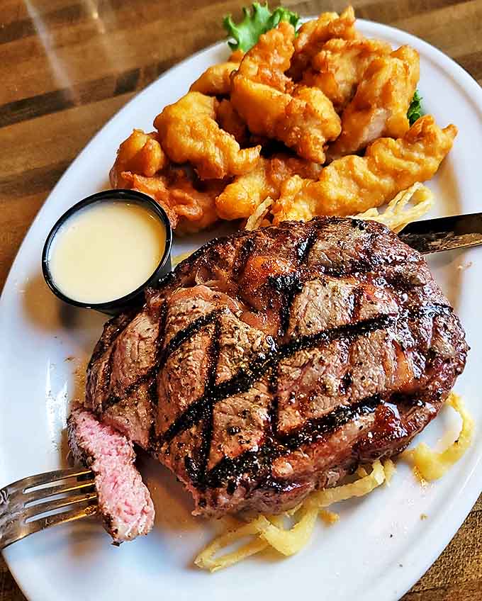 A perfectly grilled steak reveals its pink center, accompanied by golden chicken tenders &ndash; proof that land animals didn't sacrifice themselves in vain.