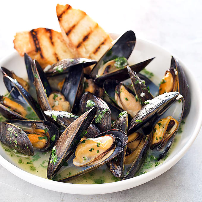 Steamed mussels in garlic butter broth with grilled bread for soaking up every last drop of liquid gold.
