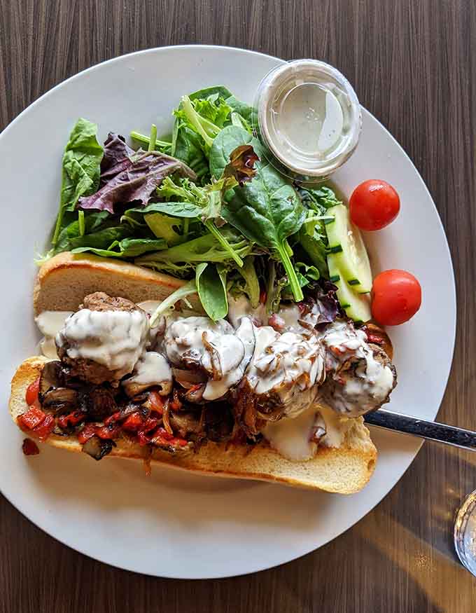 The bison meatball sandwich arrives as an open-faced masterpiece, loaded with melted cheese and fresh greens that'll make your taste buds sing.