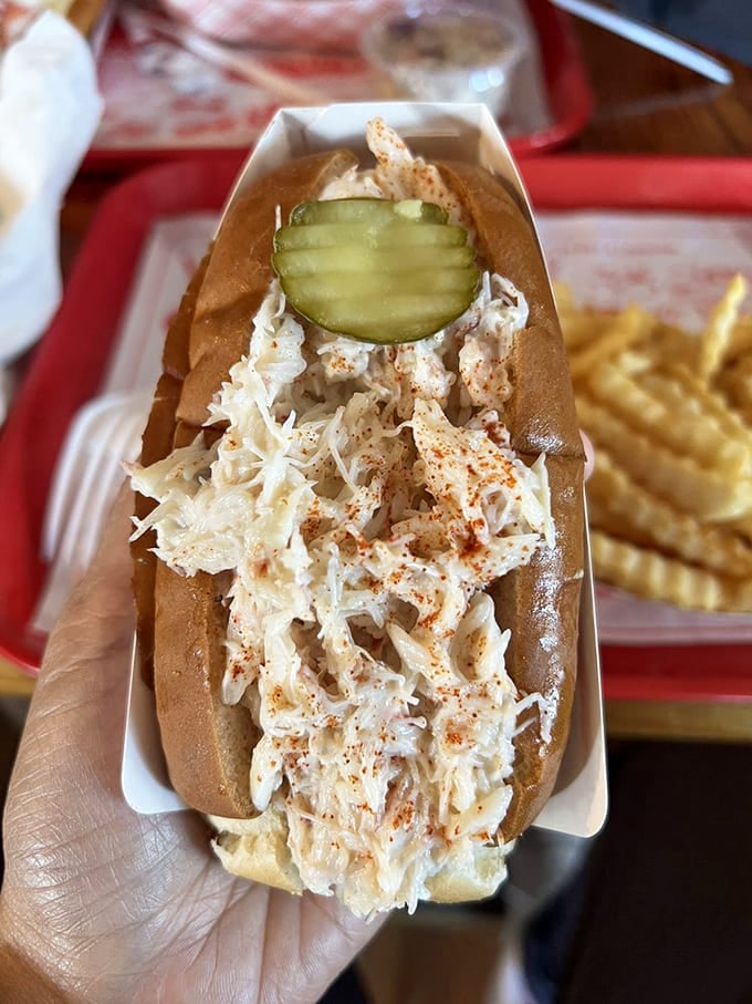Crab roll perfection with a pickle on top, because even crustaceans deserve proper garnishing and a moment in the spotlight.