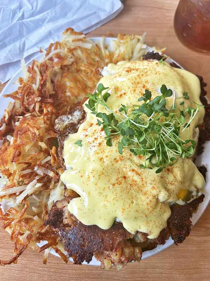 Hash browns form a golden foundation for this masterpiece, where corned beef and eggs unite under a blanket of melted cheese and fresh microgreens.