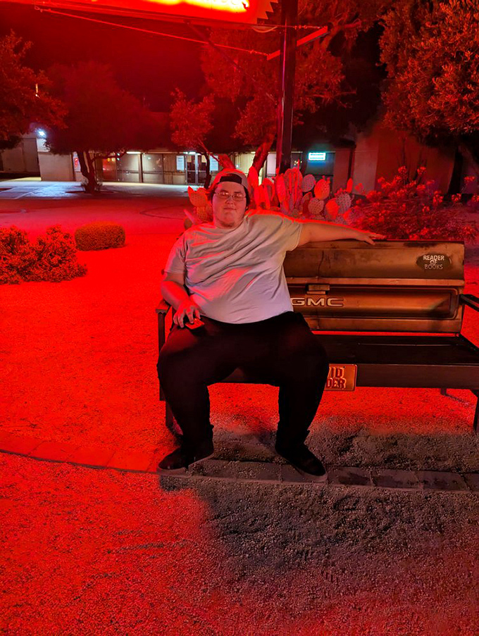 Even visitors can't resist becoming part of the neon landscape, bathed in the crimson glow that transforms ordinary moments into scenes from an American road movie.