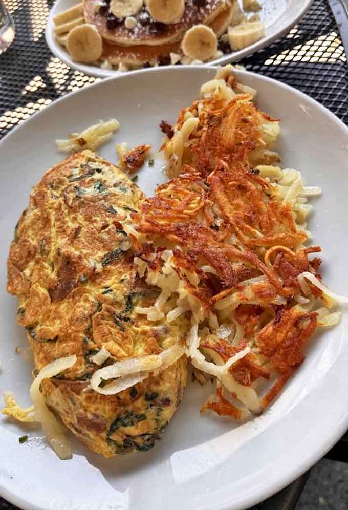 This omelet doesn't just contain ingredients; it showcases them, with each bite offering a perfect balance of eggs and fillings alongside crispy hash browns.