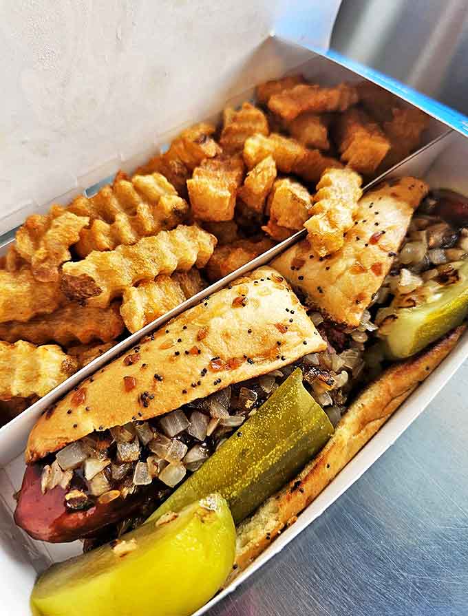 A beautifully assembled Chicago-style hot dog with its colorful toppings creating a flavor symphony that's been perfected over decades of service.