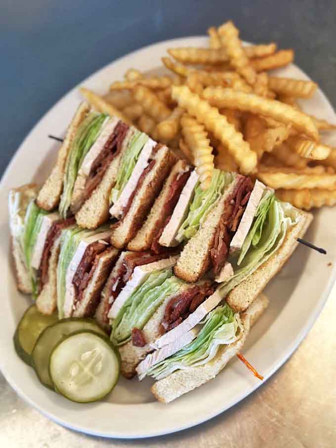 The club sandwich &ndash; architectural marvel of layered meats, crisp lettuce, and toast that requires both hands and possibly an engineering degree.