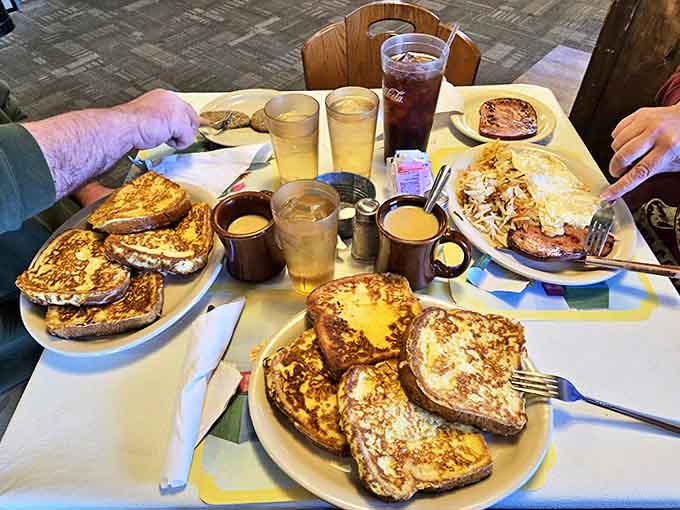 Golden French toast stacked high enough to cast its own shadow, accompanied by eggs cooked exactly the way you like them.