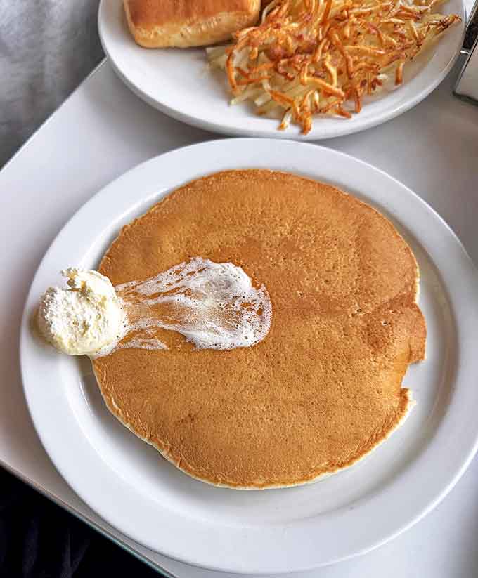 Pancakes so perfectly golden they make you wonder if the sun itself had a hand in their creation. That melting butter pat is performing a slow, delicious dance.