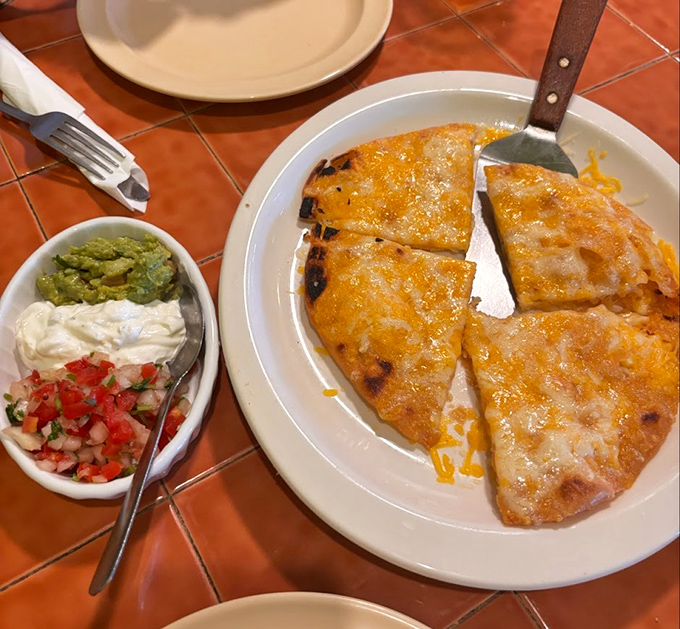 A quesadilla that achieves the golden trifecta: perfectly crisp exterior, molten cheese interior, and those essential sides for customizing each bite.
