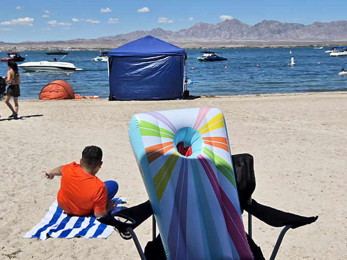 Colorful beach gear dots the shoreline as visitors stake their claim to this unexpected desert paradise, just 15 miles from Lake Havasu City.