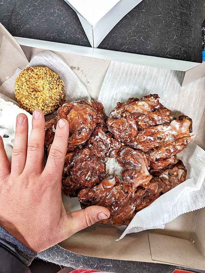 Apple fritters the size of softballs sit alongside glazed donuts, their sticky-sweet perfection practically begging to be paired with hot coffee.