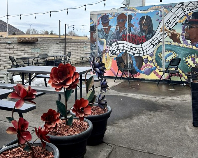 The back patio offers a musical oasis with its jazz-themed mural, string lights, and metal flower sculptures creating casual outdoor charm.