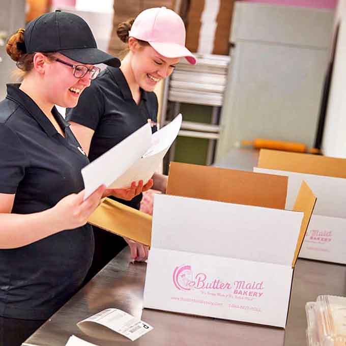 The bakery team prepares orders with practiced precision, their hands carrying the muscle memory of countless rolls shaped to perfection.