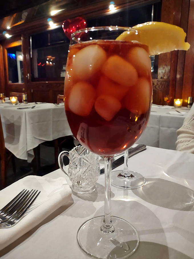 Cheers to exceptional dining! This ruby-hued cocktail, brimming with ice and garnished with citrus, promises refreshment between heavenly bites.