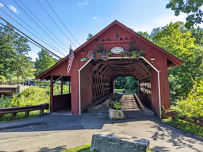 The historic Creamery Covered Bridge stands as a crimson sentinel over Whetstone Brook, its weathered timbers telling stories of Vermont's rich past.