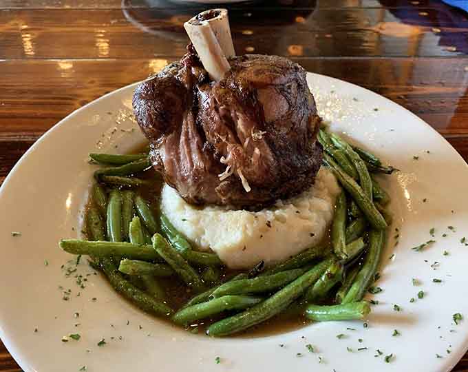 The pork shank stands tall like a delicious monument to everything right about slow-smoked meat and mashed potatoes.