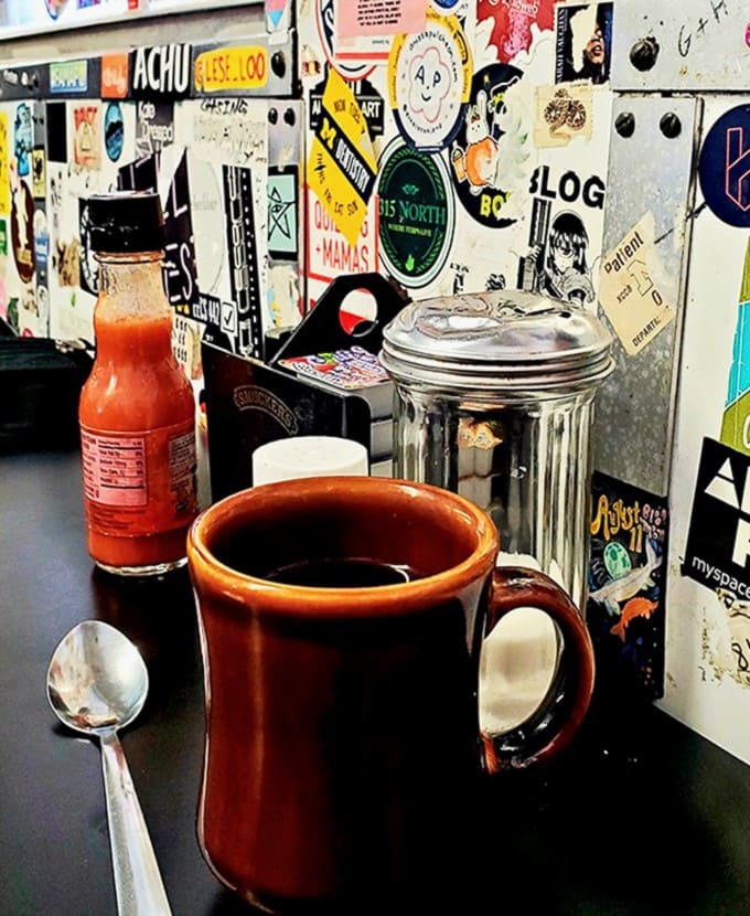 That sturdy brown mug promises bottomless refills of honest, strong coffee &ndash; the lifeblood of students, night owls, and early risers alike.