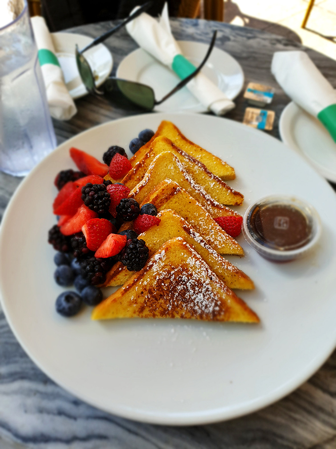 French toast triangles that could make a geometry teacher weep with joy, adorned with berries so fresh they might have been picked while you were ordering.