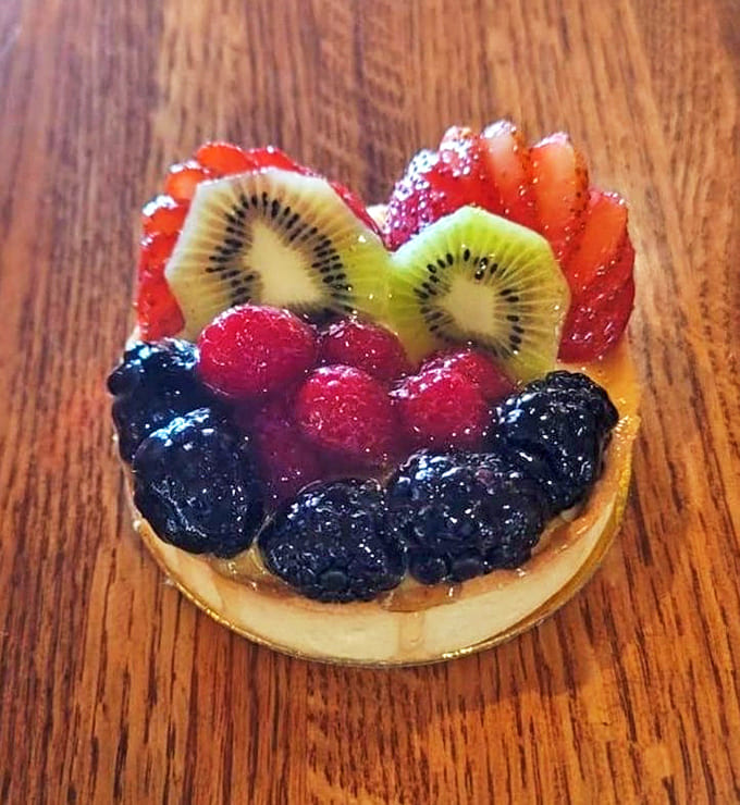 A fruit tart that's practically winking at you, crowned with berries so fresh they could've been picked moments ago.