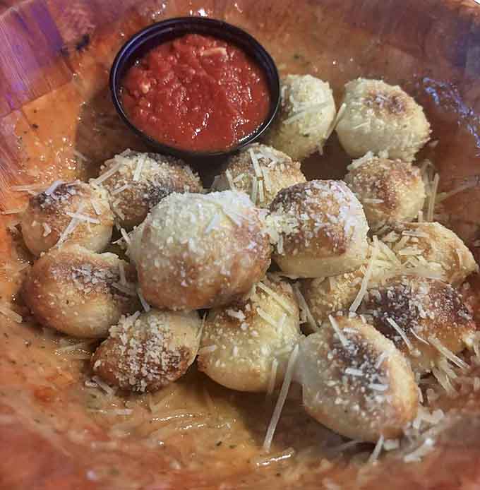 Garlic knots dusted with parmesan await their marinara bath &ndash; pillowy inside, golden outside, and utterly irresistible between games.