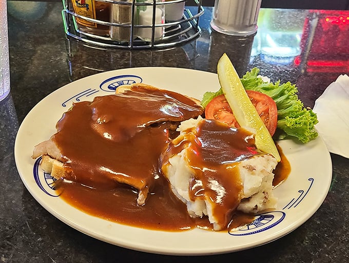Tender beef draped over bread and mashed potatoes, swimming in gravy that pools like a delicious brown lagoon of comfort.