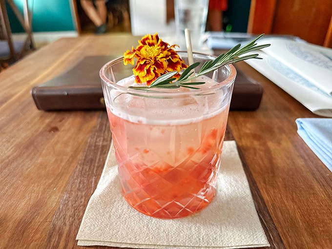 This isn't just a cocktail—it's a sunset in a glass, garnished with rosemary and edible flowers for dramatic flair.