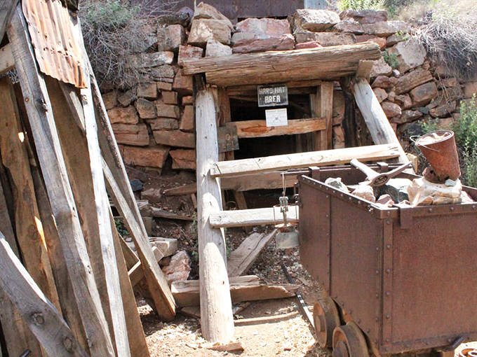 The mine entrance, supported by weathered timbers, hints at the dangerous underground world where miners sought their fortunes.