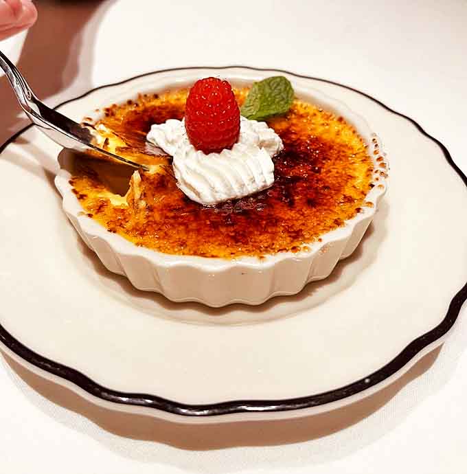 The crème brûlée's caramelized top gives that satisfying crack before revealing silky custard, topped with a perfect raspberry punctuation mark.