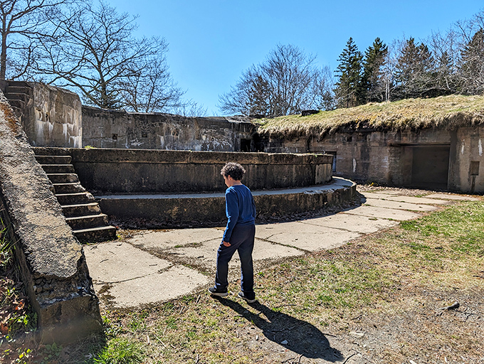 A solitary visitor contemplates the fort's curved concrete platforms, where soldiers once stood ready to defend Maine's vulnerable coastline.