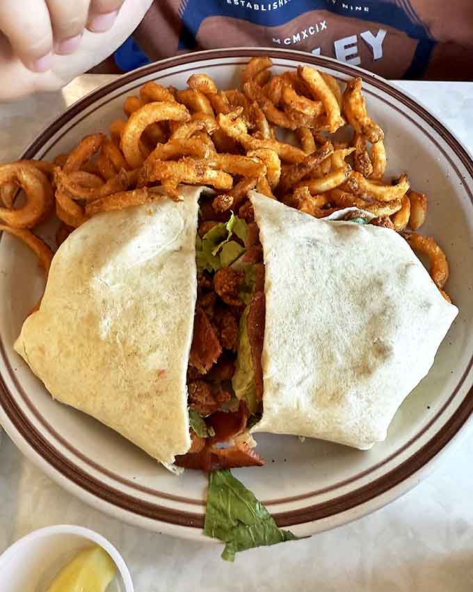 This wrap isn't messing around &ndash; packed tight with savory fillings and paired with curly fries that perform perfect springy spirals from plate to mouth.