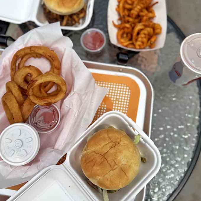 A feast fit for road warriors: juicy burgers nestled in paper containers alongside golden onion rings that practically beg to be photographed.